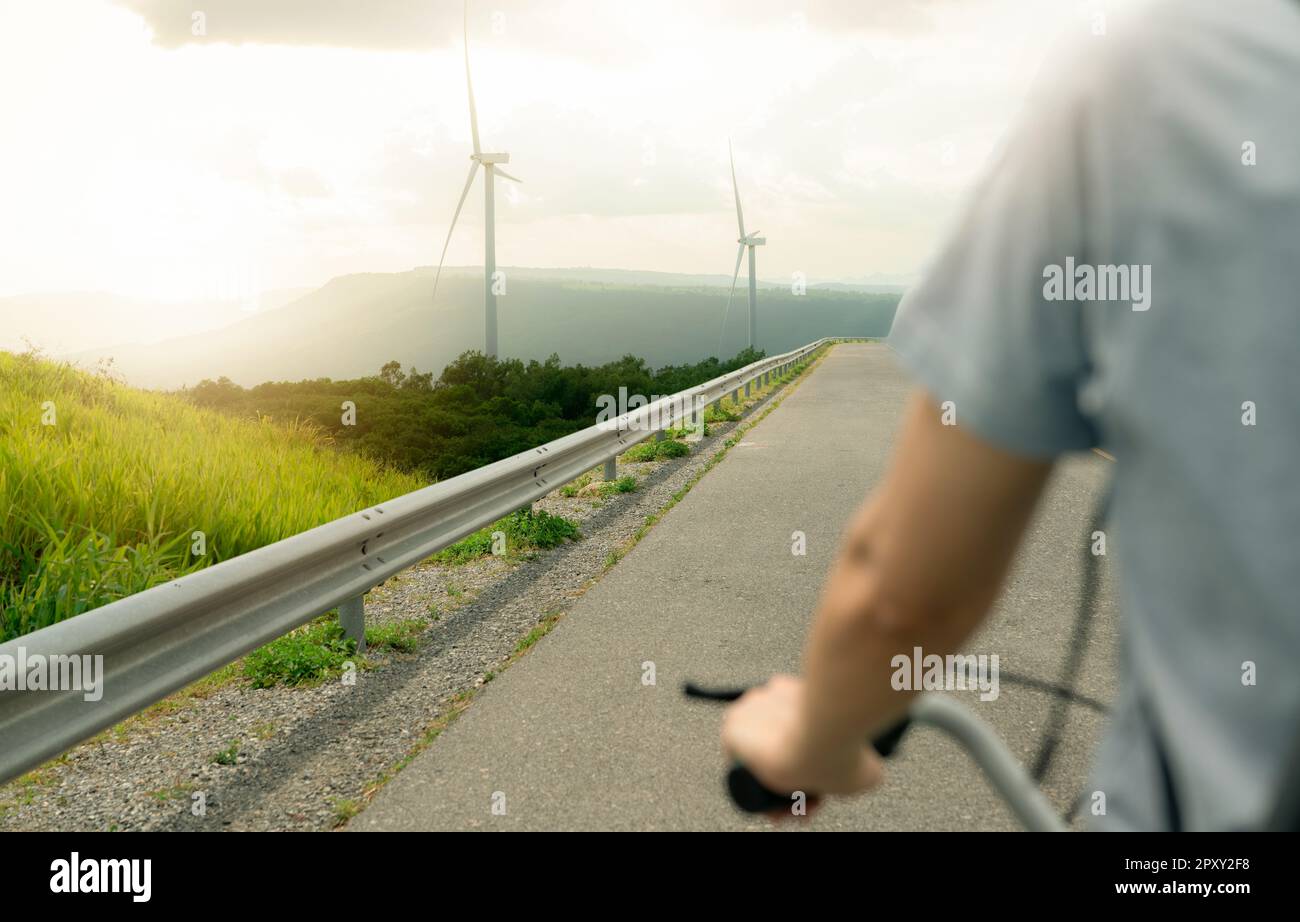Selective focus on wind farm with rearview of person riding a bicycle ...