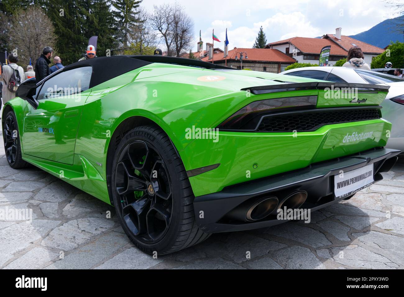 A vibrant lime-colored Lamborghini sports car is parked on a red-brick ...