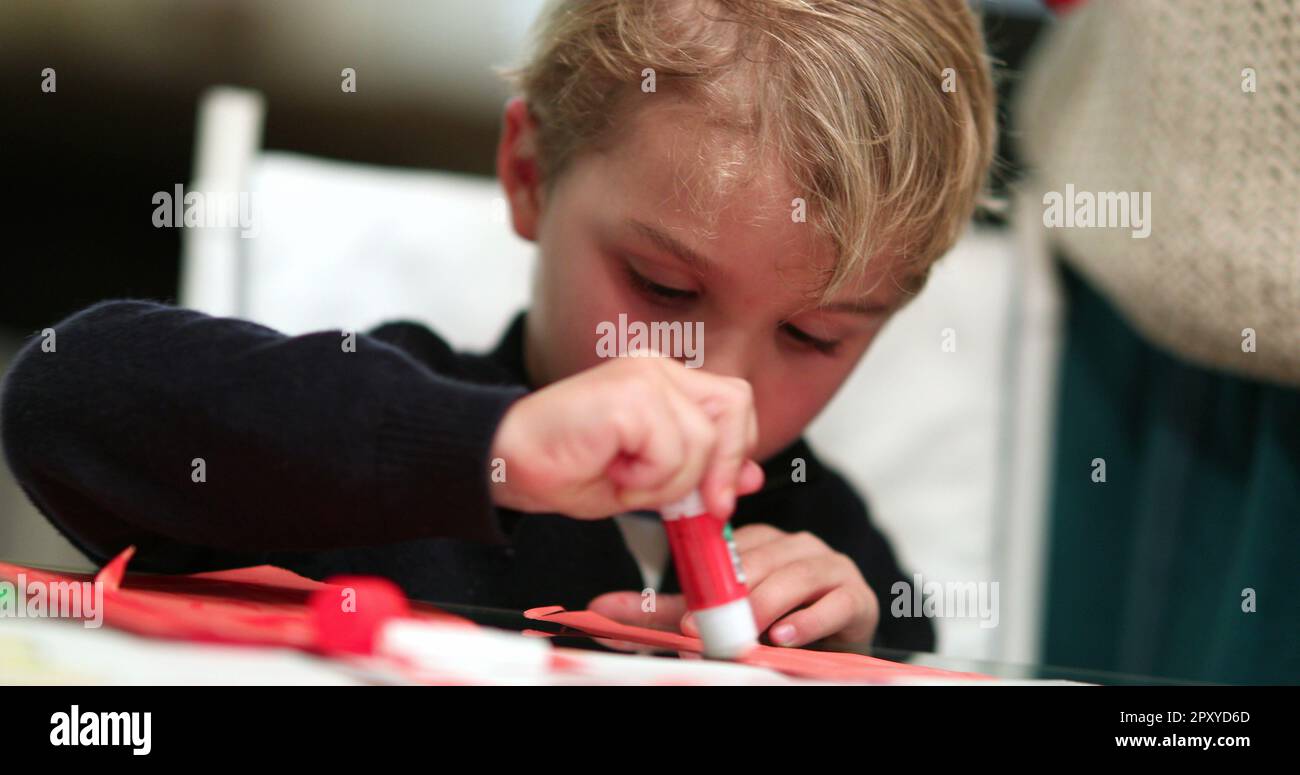 Child crafting and creating at home, kid gluing paper with glue Stock ...