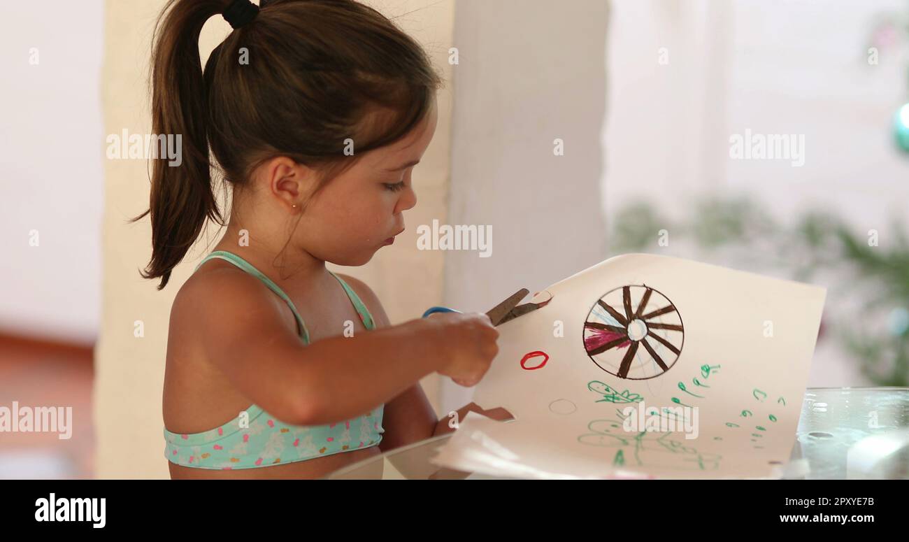 Child girl cutting paper drawing with scissors, kid crafting and ...