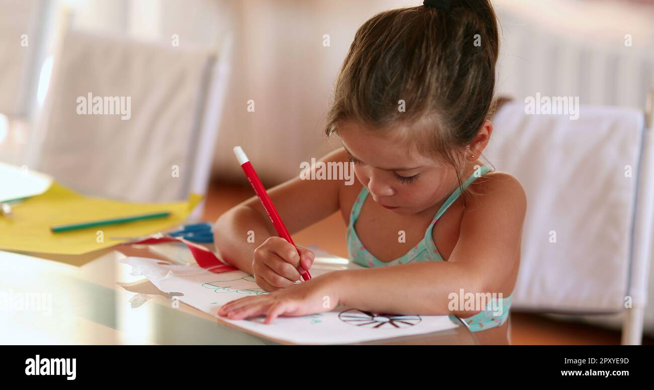 Child girl drawing with red color pen on paper at home. Focused ...