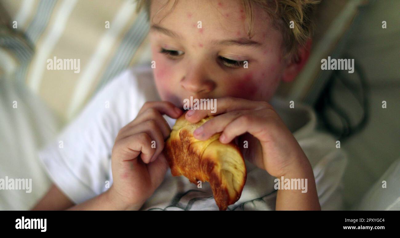 Handsome pensive child toddler boy thinking while eating croissant ...