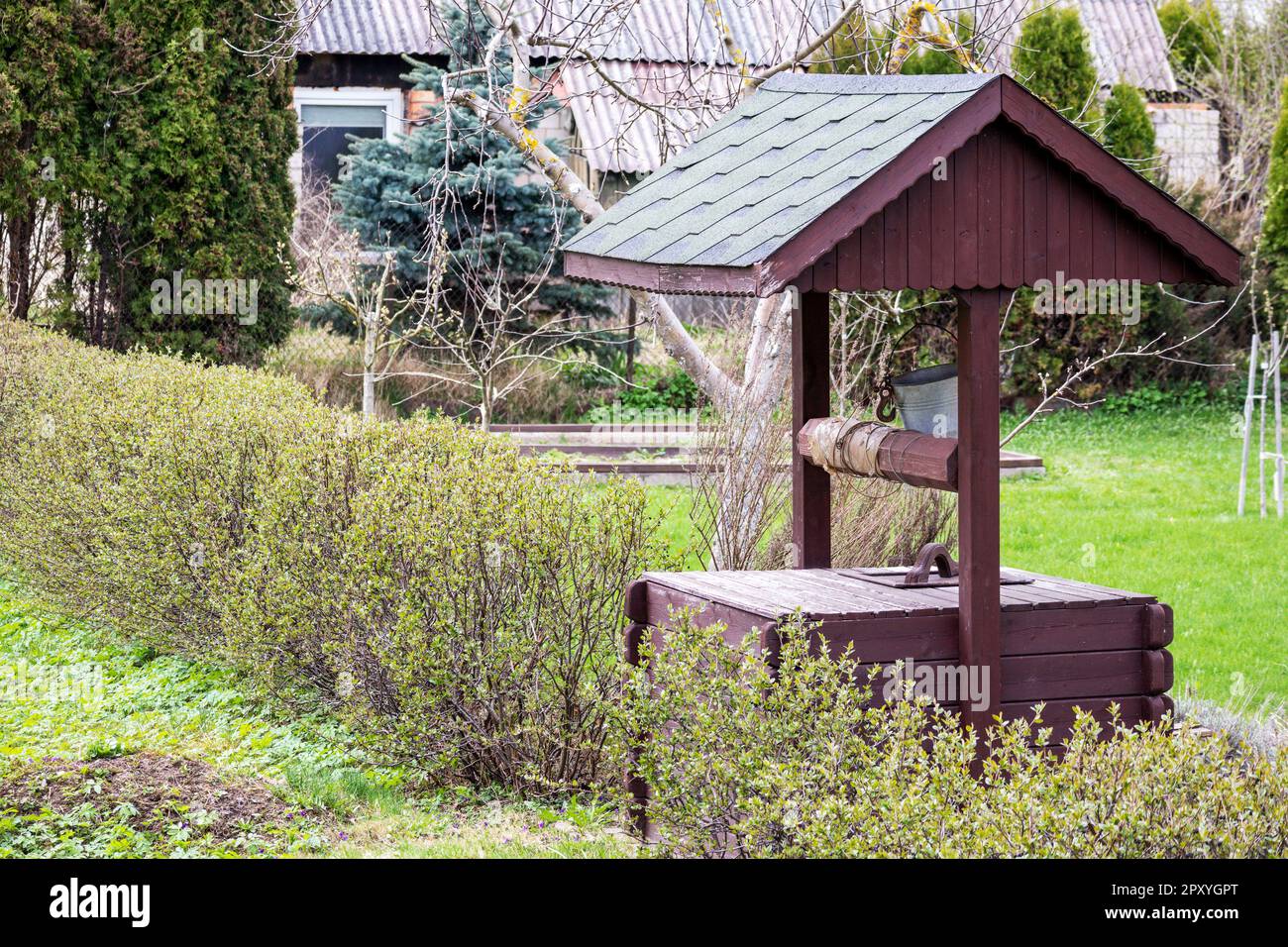 A wooden water well with a green roof sits in a garden Stock Photo - Alamy