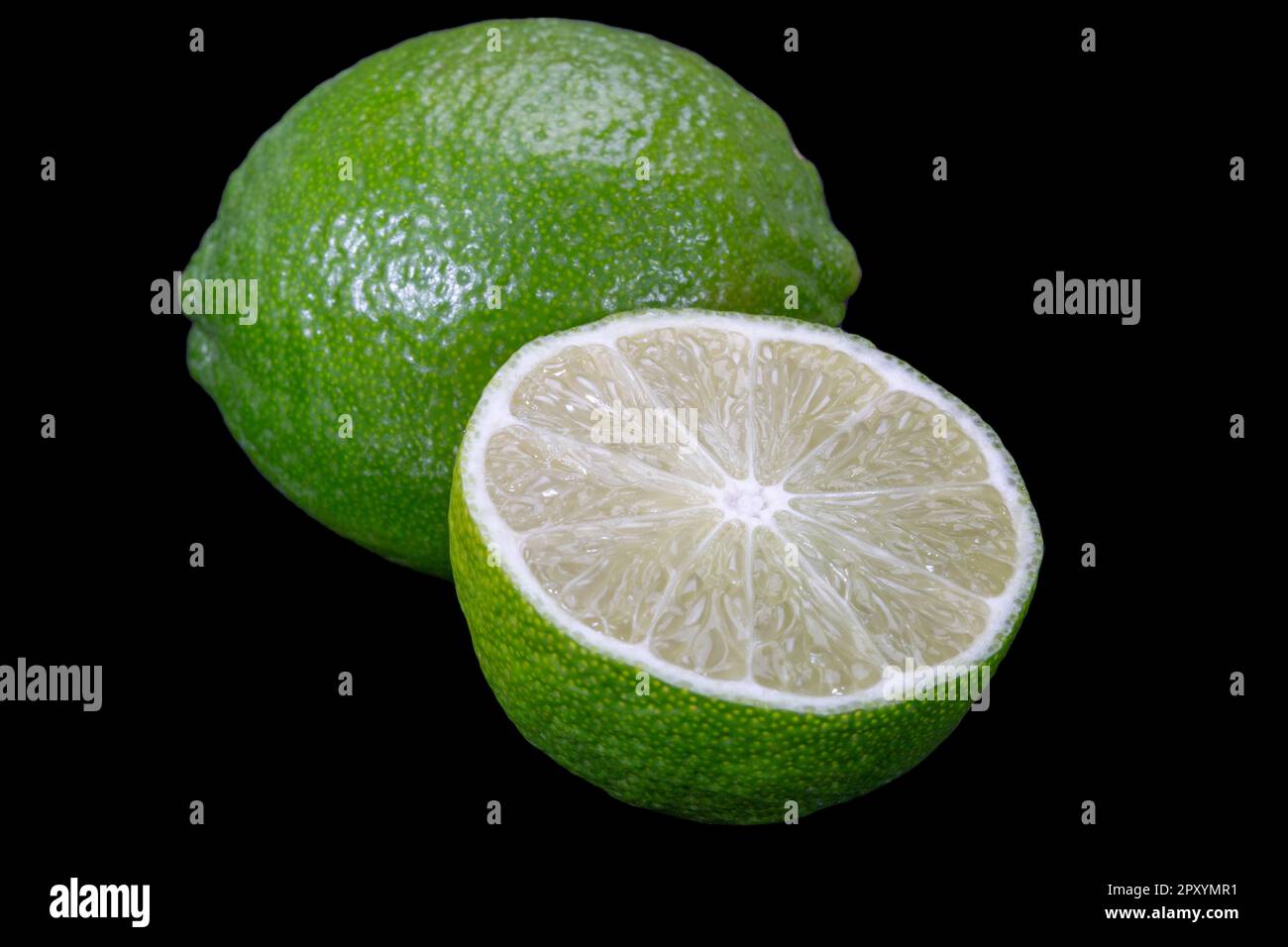 Whole and half of green lime isolated on black background, close up ...