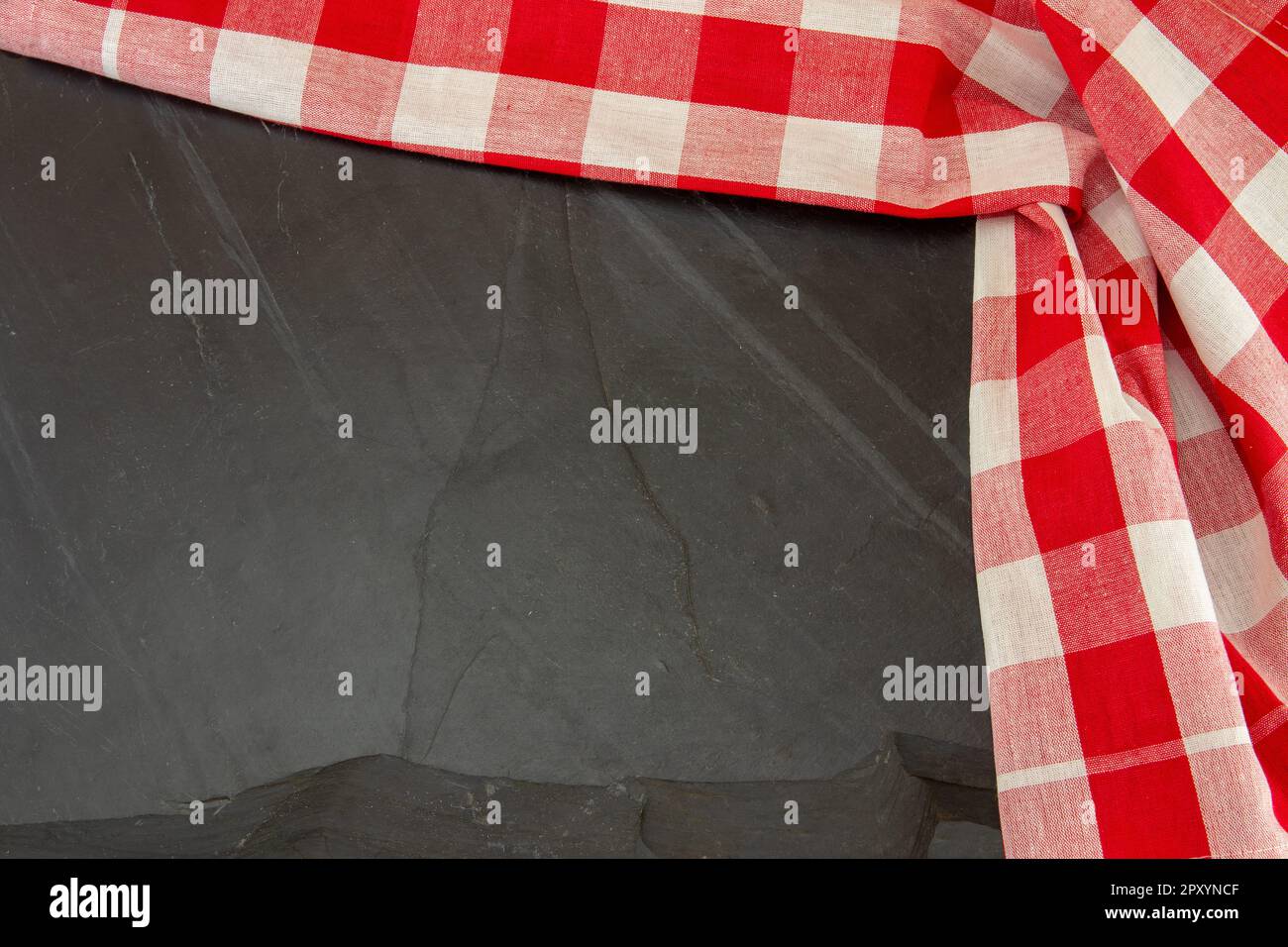 Red white checkered tablecloth on massive slate plate or black stone ...