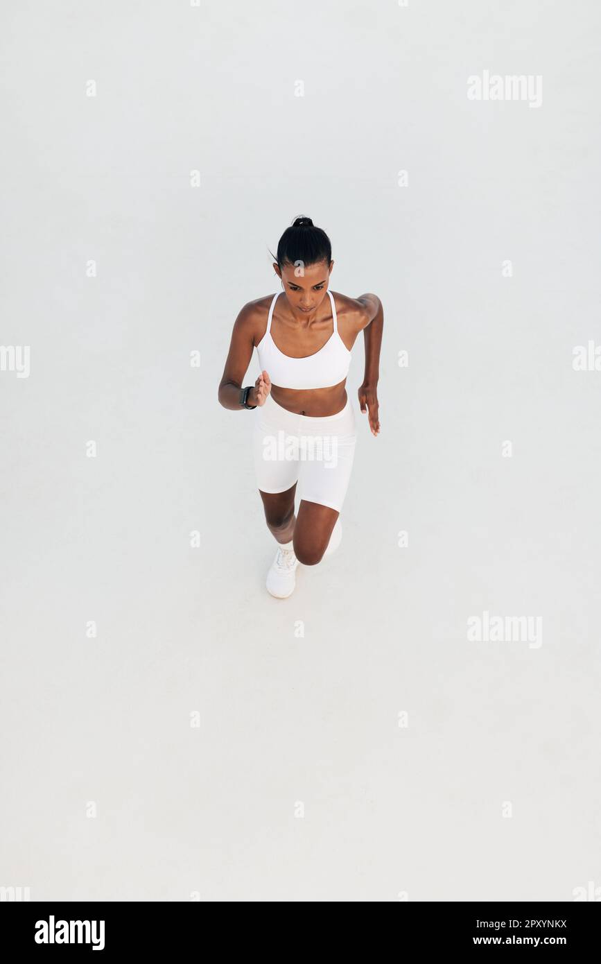 Shot from above of a young woman running in a white outdoor studio ...