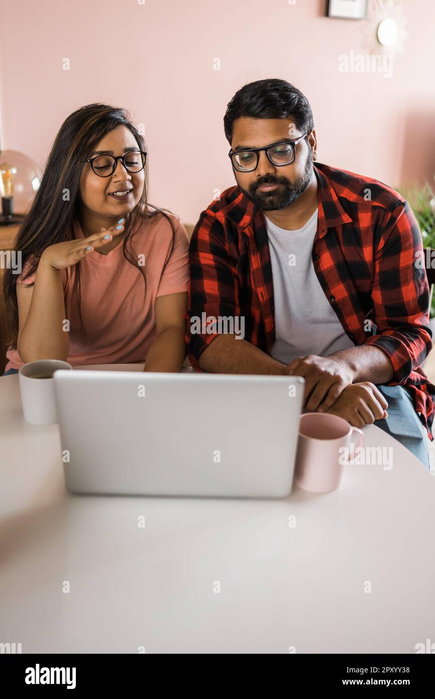 Happy indian family couple cuddle at desk make video call to friends ...