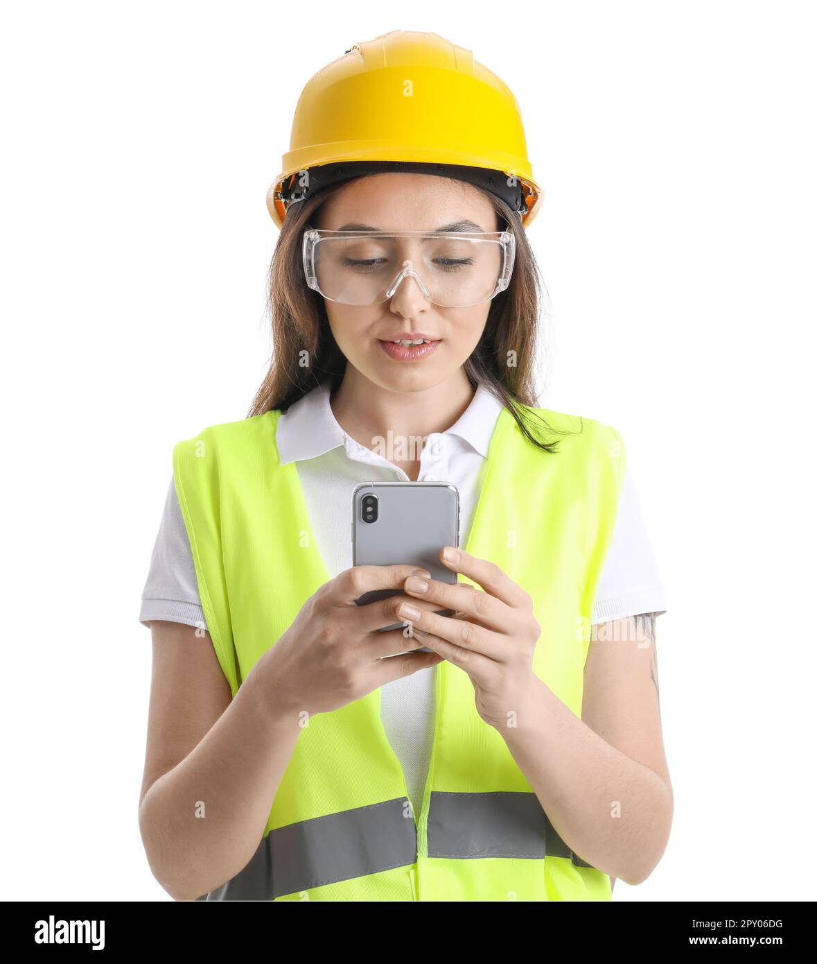 Female worker in vest and hardhat holding mobile phone on white ...