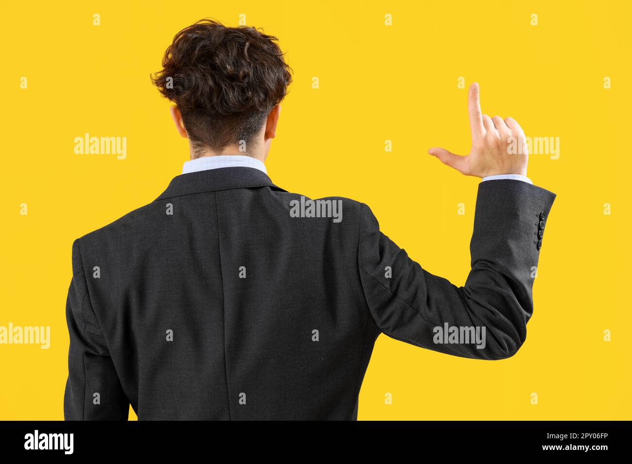 Young businessman showing loser gesture on yellow background, back view ...