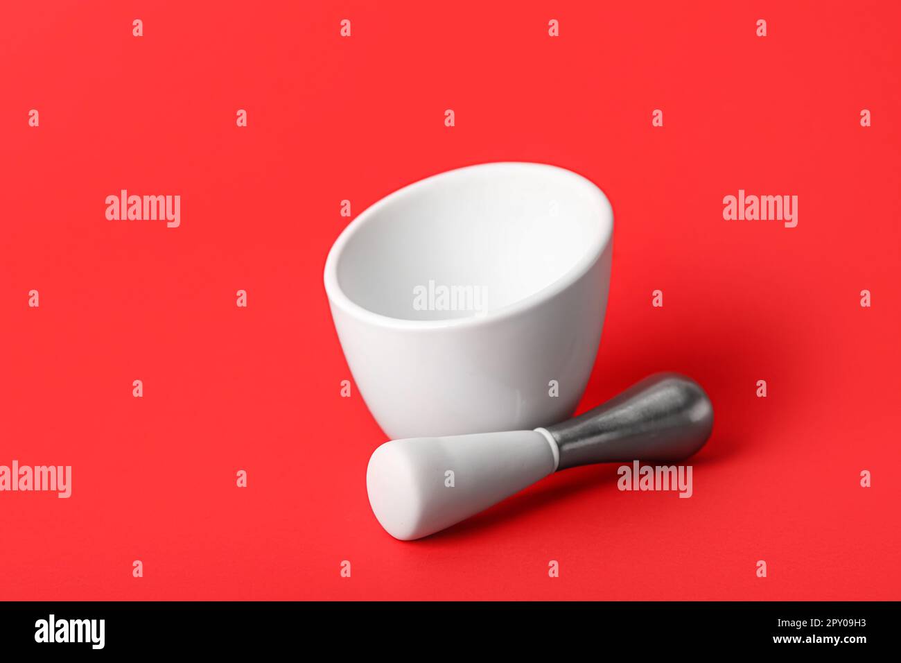 Mortar and pestle on red background Stock Photo - Alamy