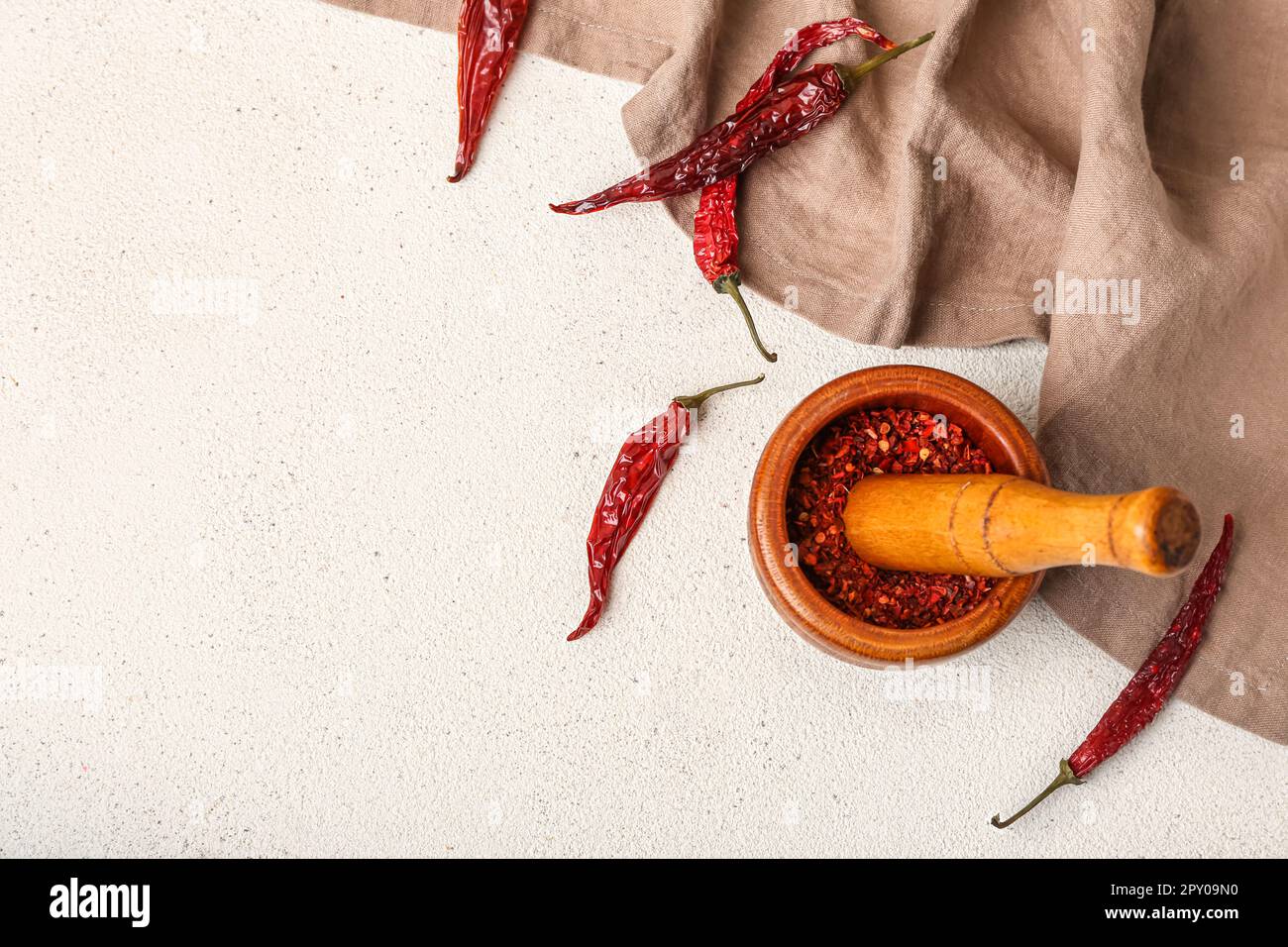 Wooden mortar and pestle with dry chili pepper on light background ...