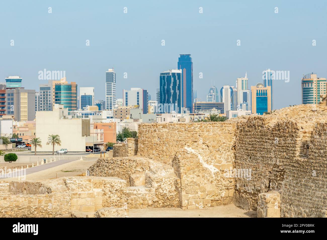 Ruins of Qalat al-Bahrain portuguese fortress with downtown in the ...