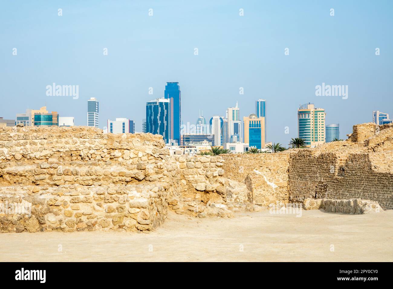 Ruins of Qalat al-Bahrain portuguese fortress with downtown in the ...