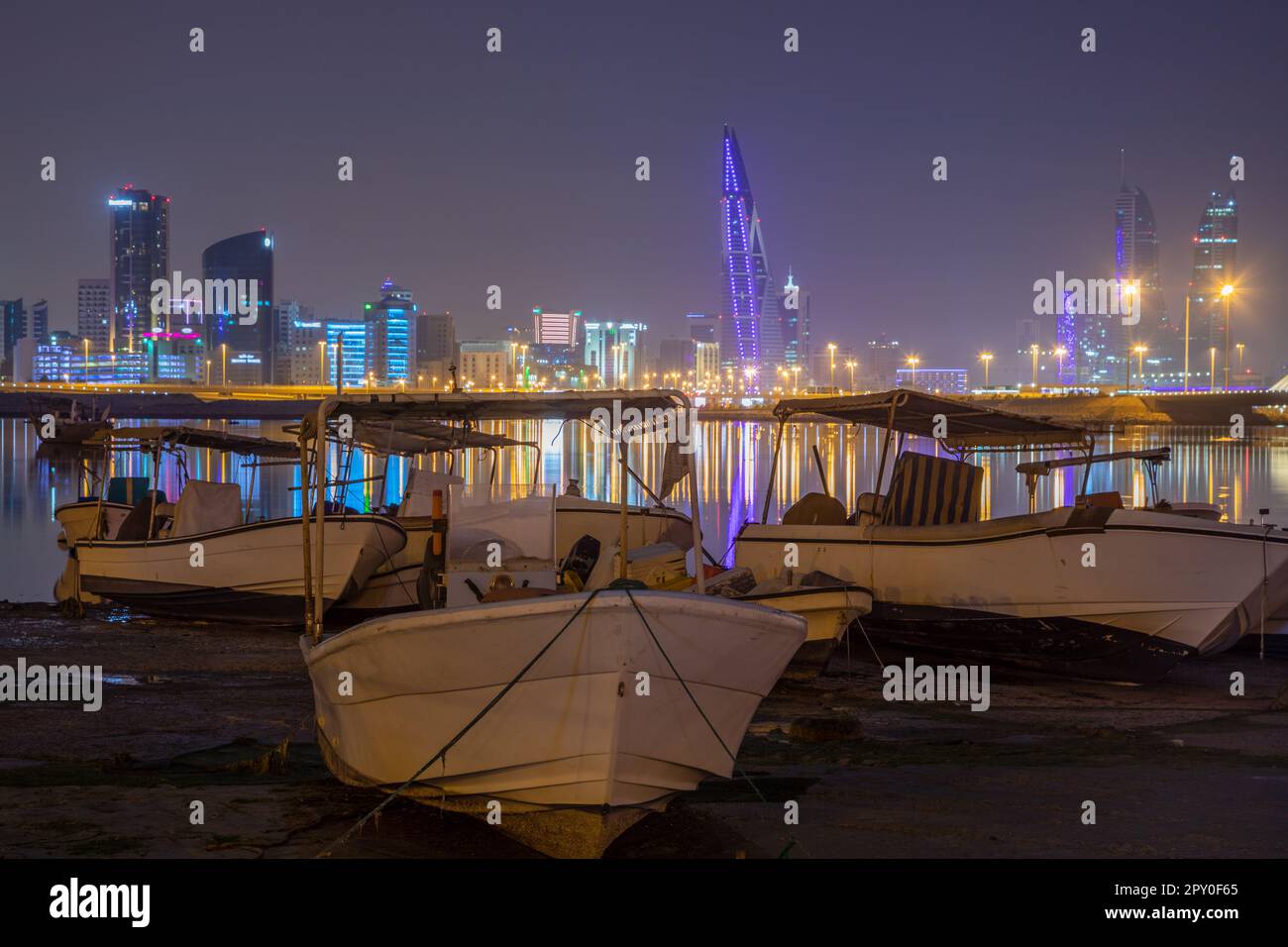 Motor boats on the shore of Persian Gulf with illuminated downtown in ...
