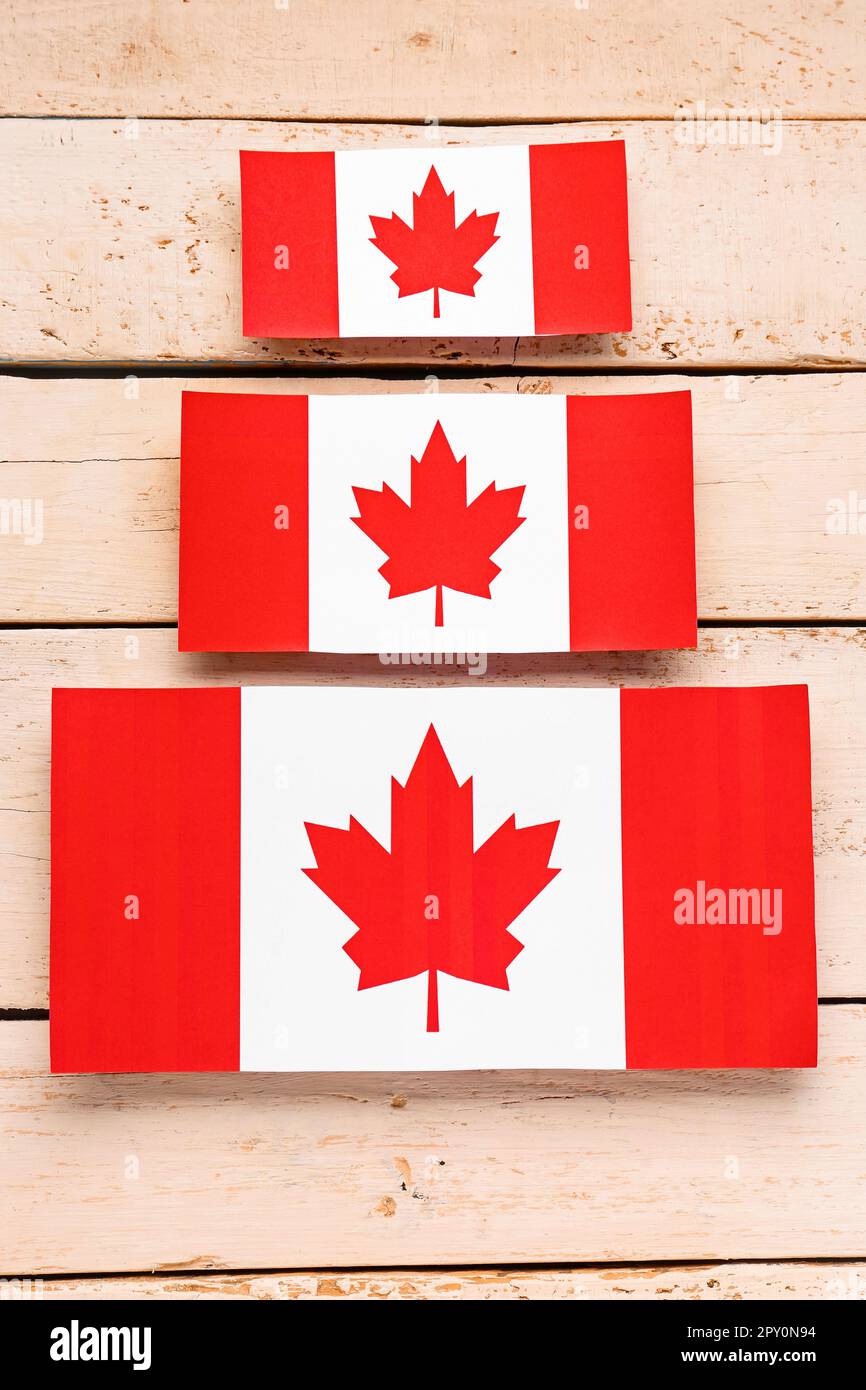 Paper flags of Canada on white wooden background Stock Photo - Alamy