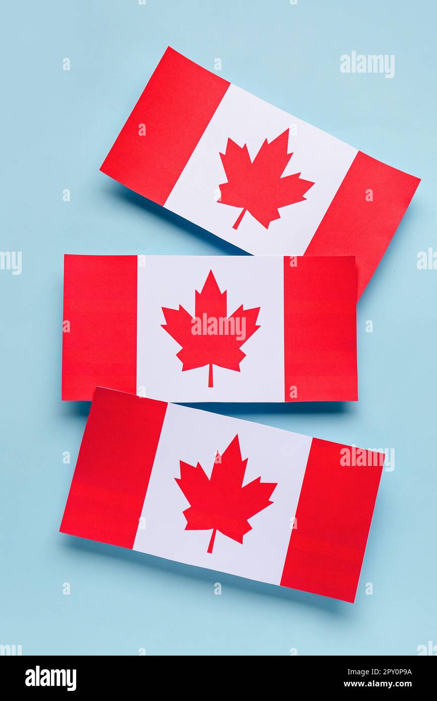 Paper flags of Canada on blue background Stock Photo - Alamy