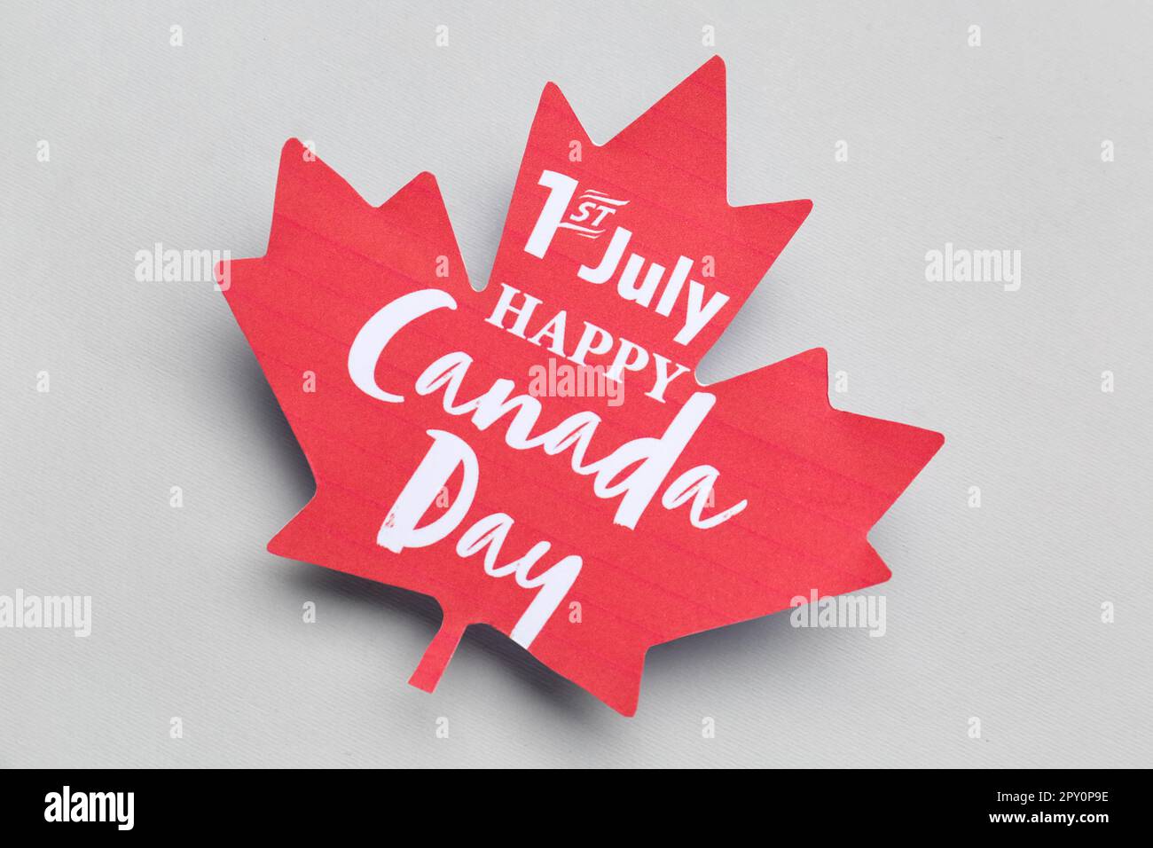 Paper maple leaf with text 1ST JULY HAPPY CANADA DAY on grey background ...