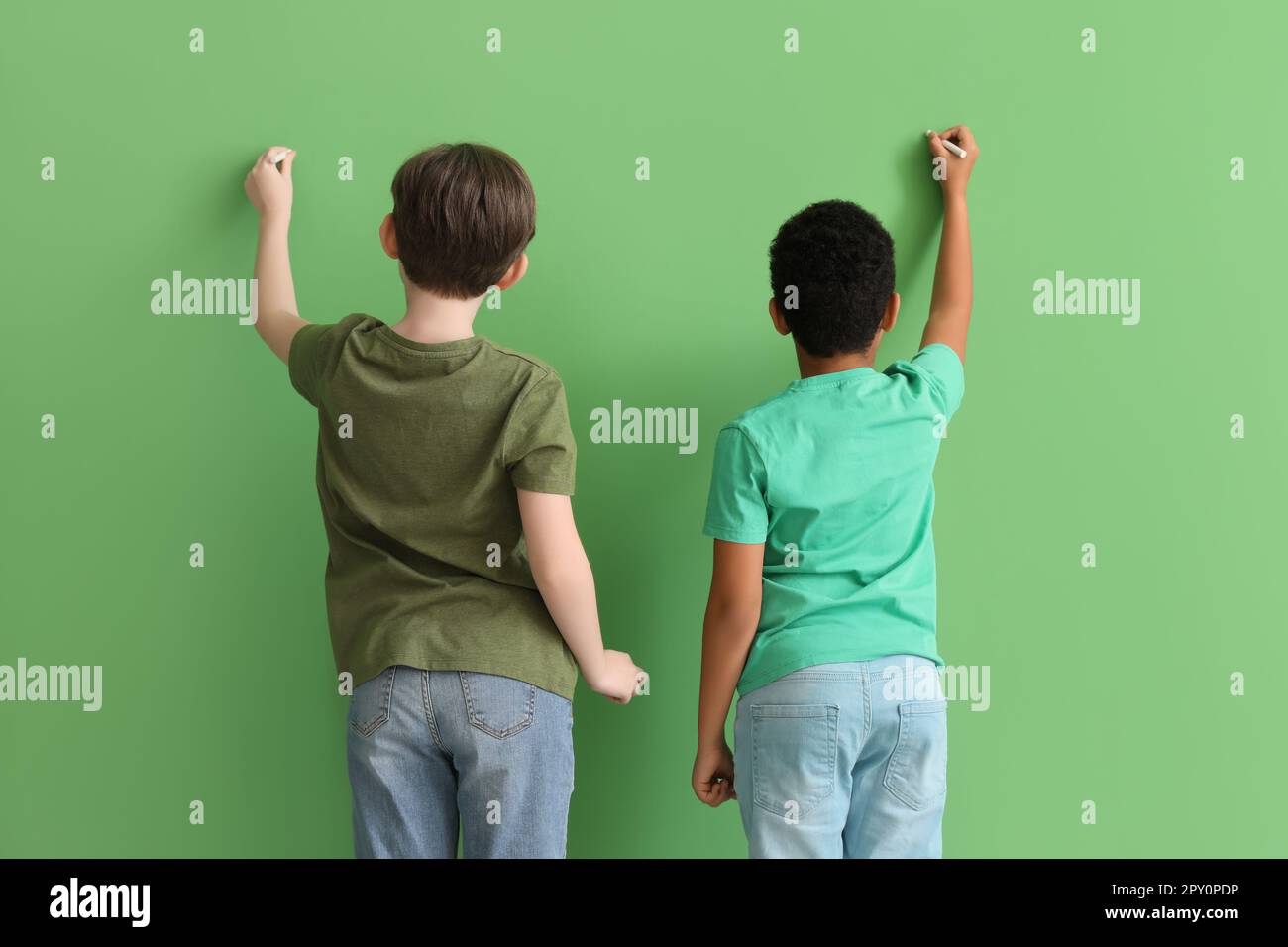 Little boys drawing with chalk pieces on green background, back view ...