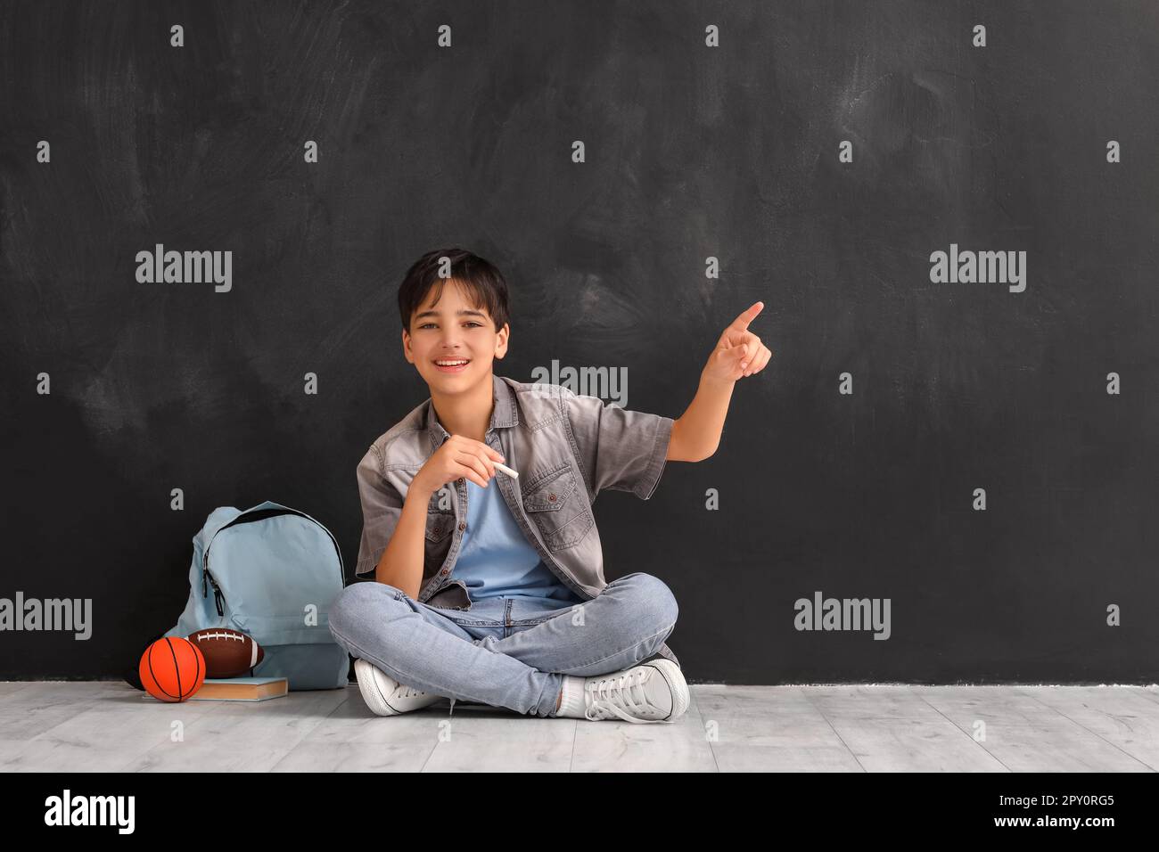 Little boy pointing at something near blackboard. Children's Day ...