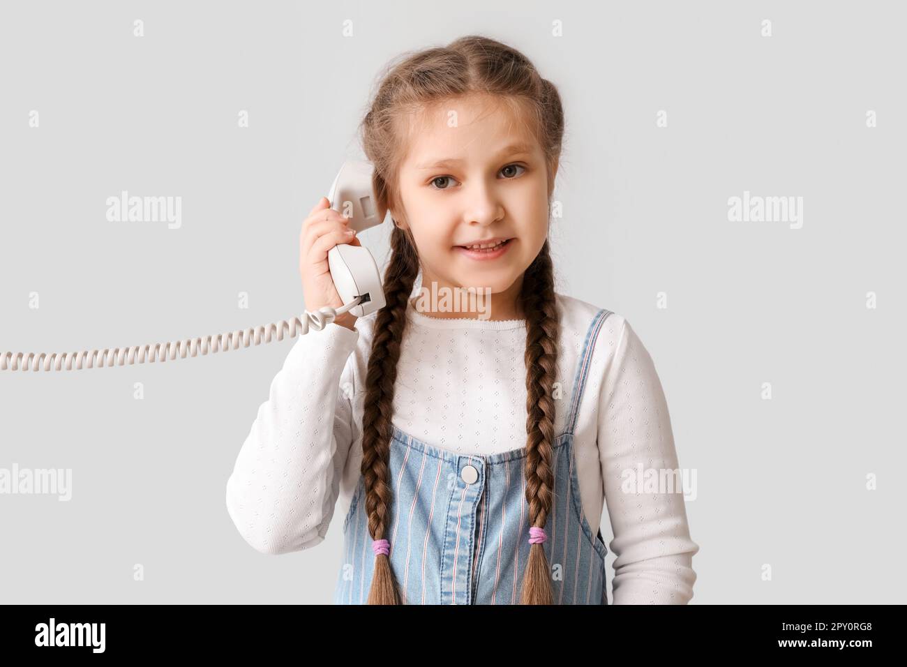 Little girl talking by telephone on light background. Children's Day ...
