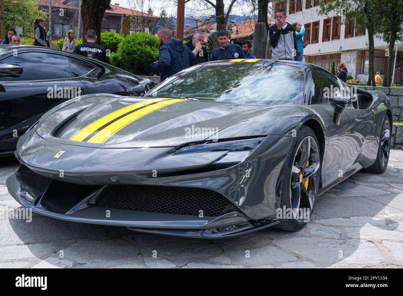 An iconic Ferrari automobile is parked in a bustling city square ...