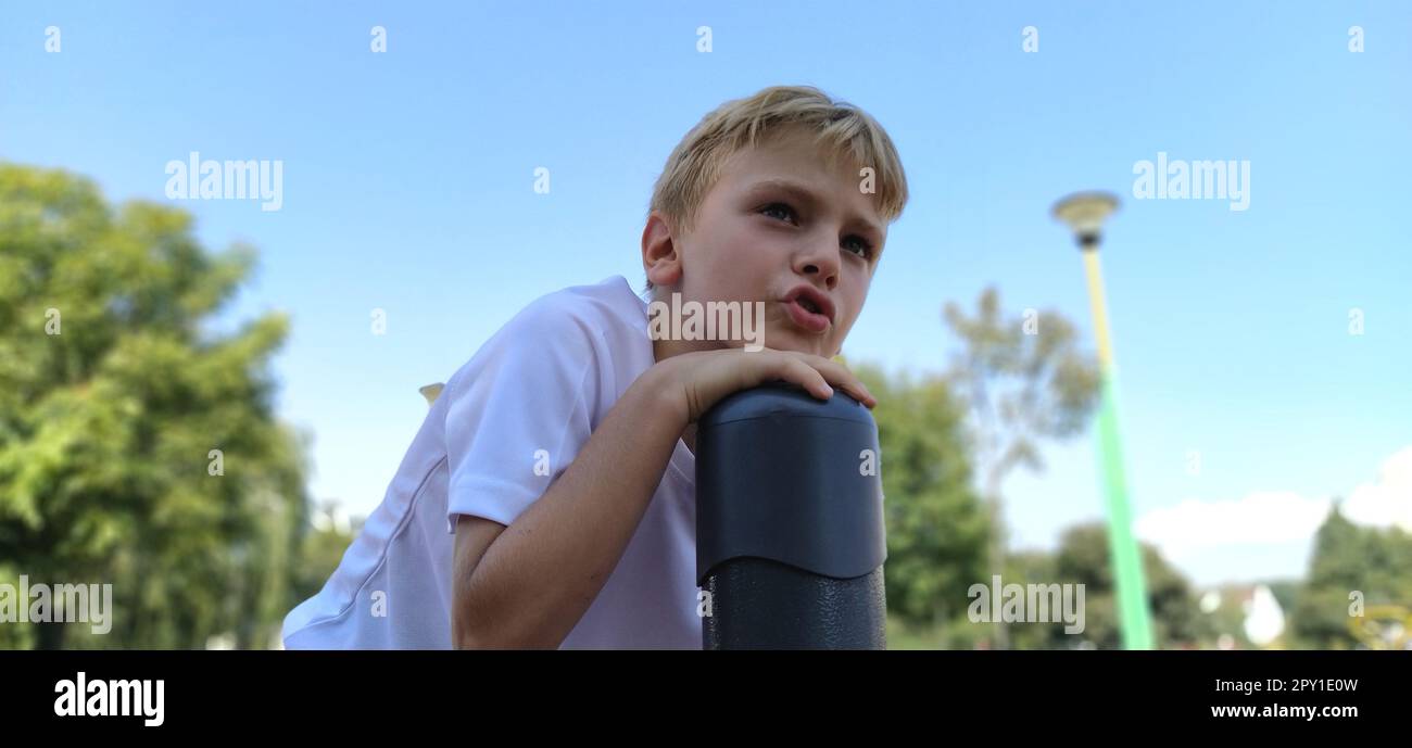 Pensive boy on the playground. The child lingered on top of the metal ...