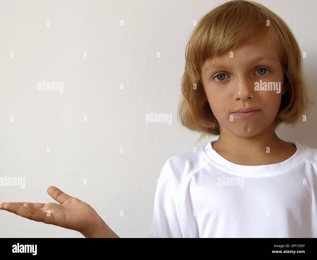 A little cute girl 6-7 years old with blond hair expresses emotional ...