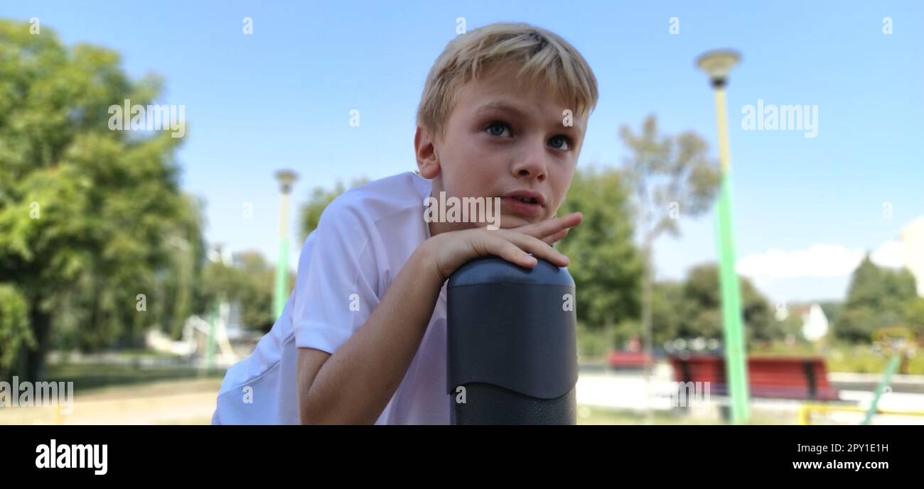 Pensive boy on the playground. The child lingered on top of the metal ...