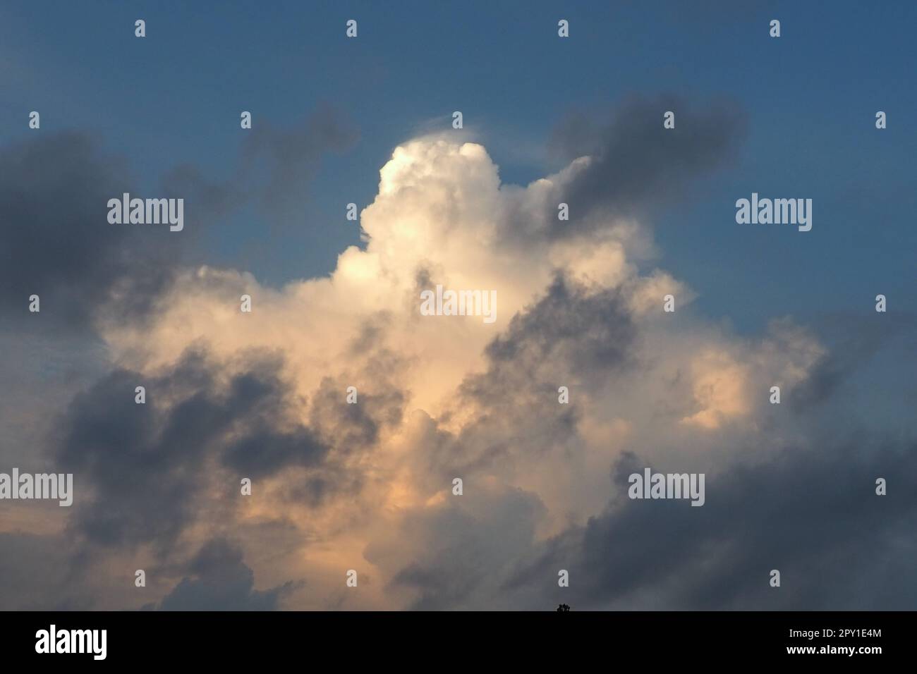 A beautiful cloud illuminated by sun during sunset. Blue sky and dark ...