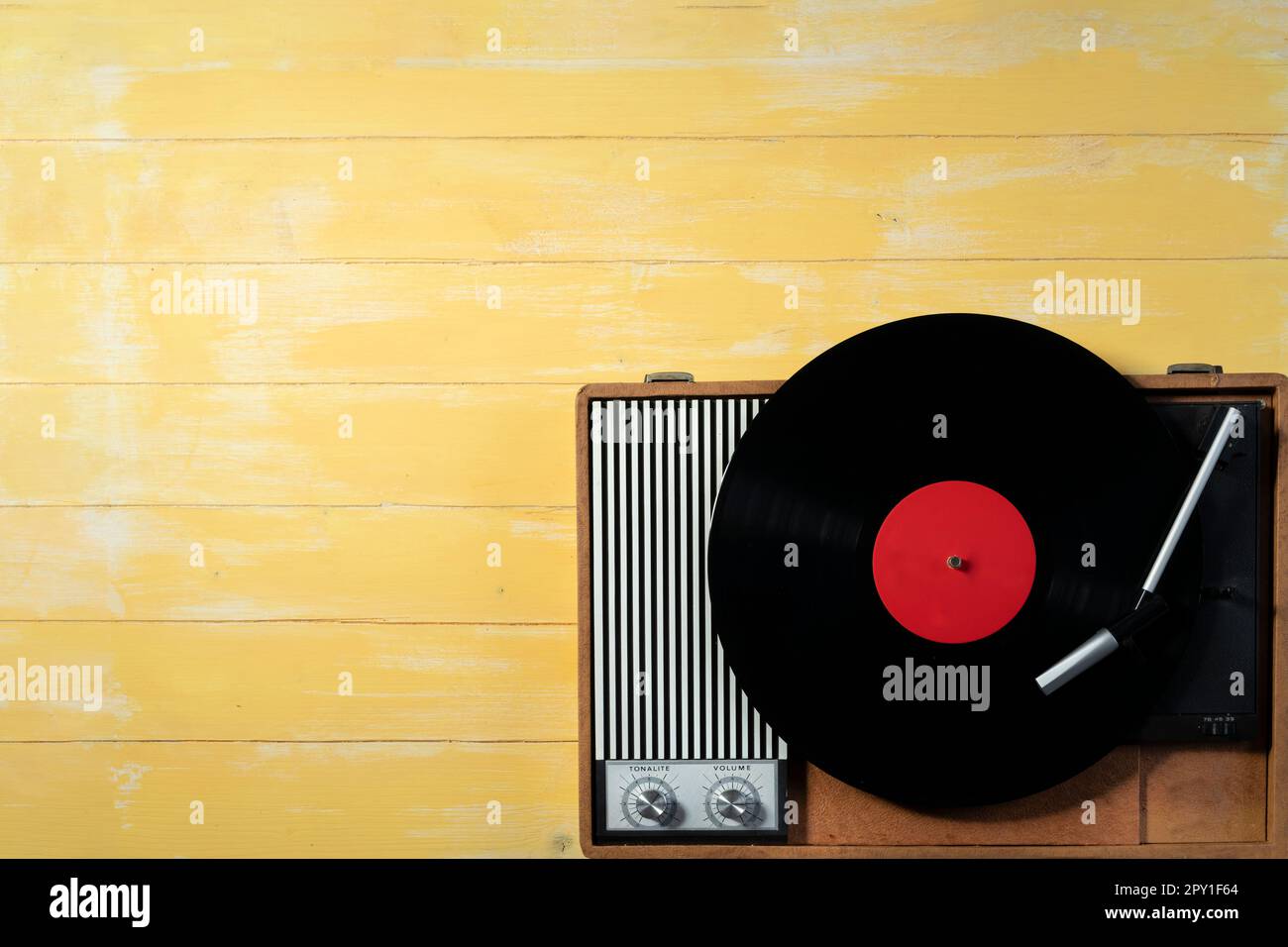 Vintage gramophone with a vinyl record on yellow wooden table, top view ...