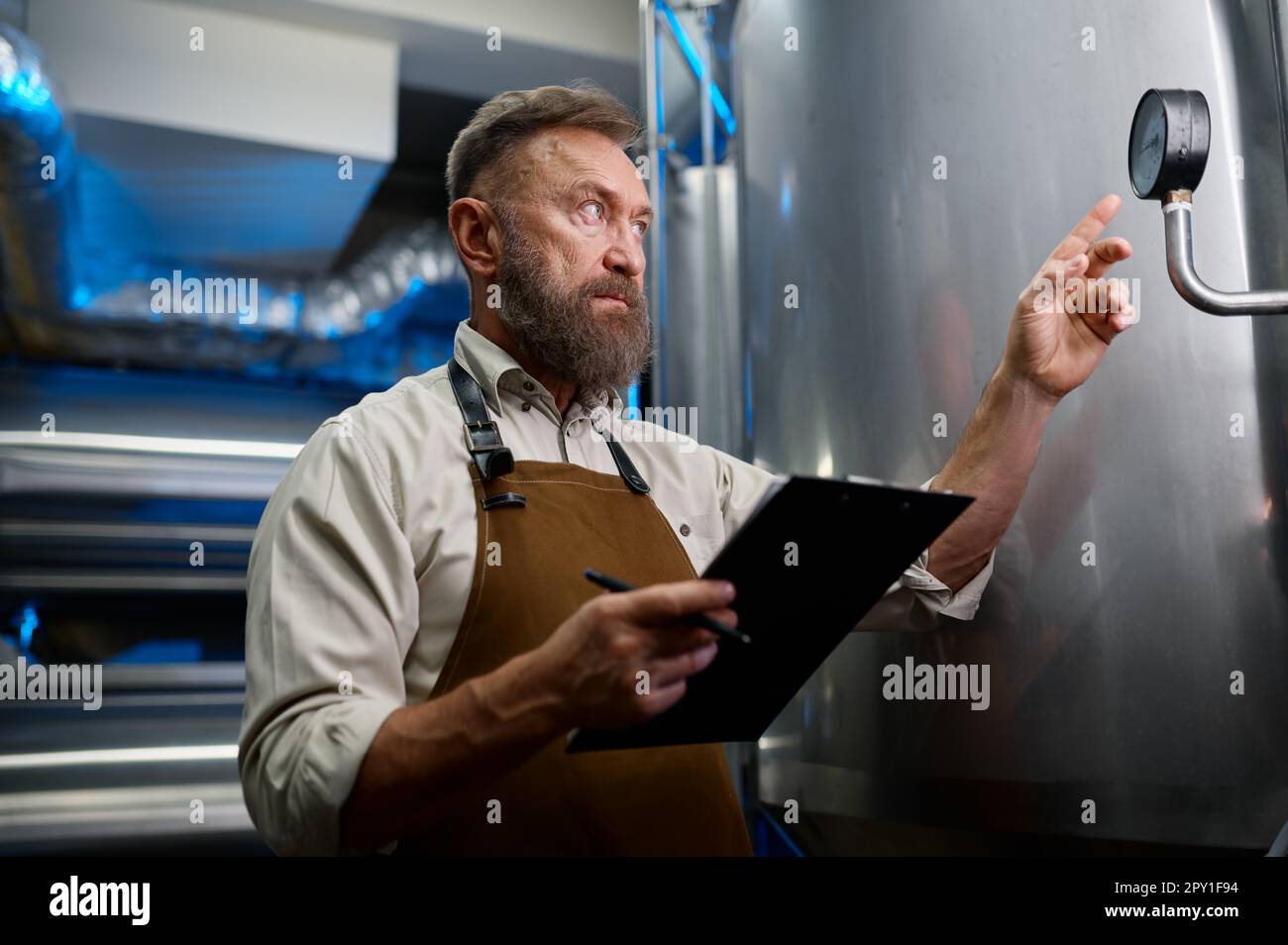 Mature man checking gauge valve indicator of distillery vats. Brewer ...