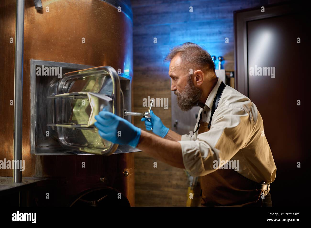 Man brewer examining beer reservoir inspecting process of brewing ...