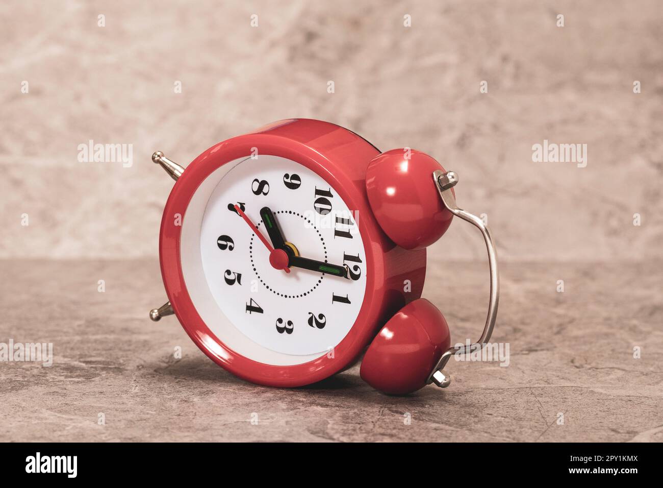 Overturned red alarm clock lying on the grey stone background Stock ...