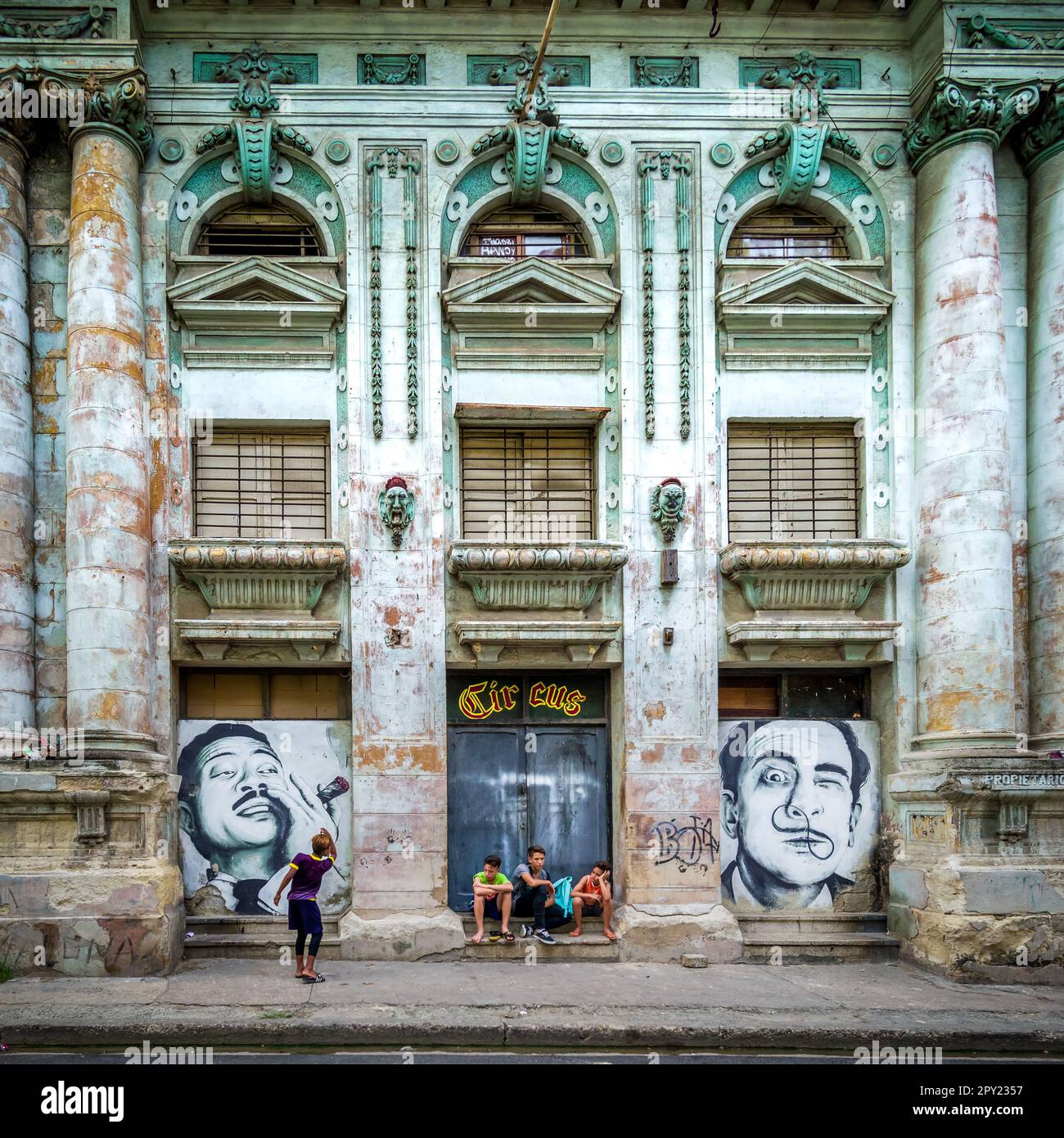 Four children playing in front of an old building with some graffities ...
