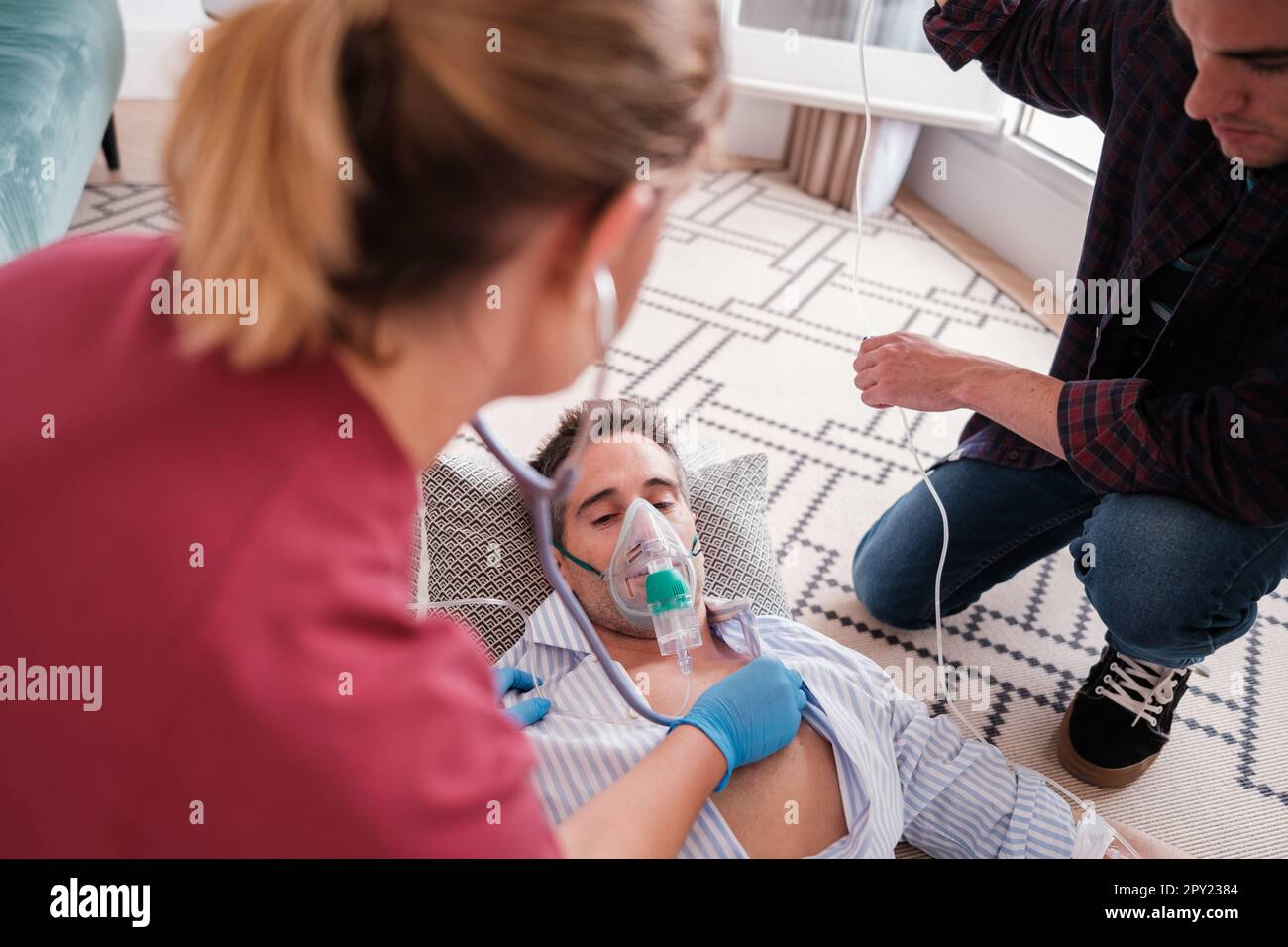 Young man receiving emergency medical attention from a doctor at home ...