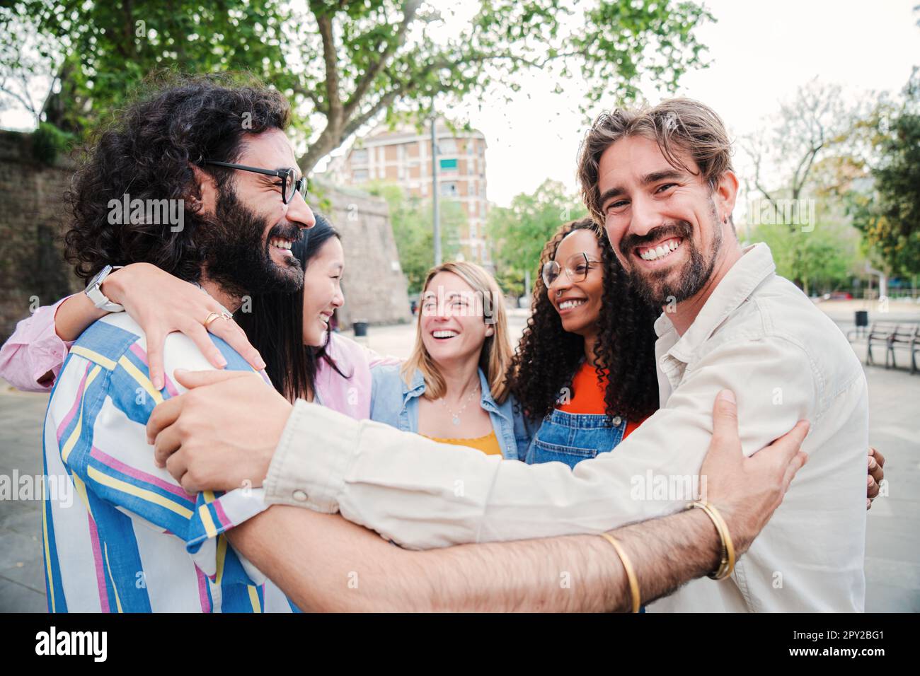 Group of young adult multiracial people having fun together hugging ...