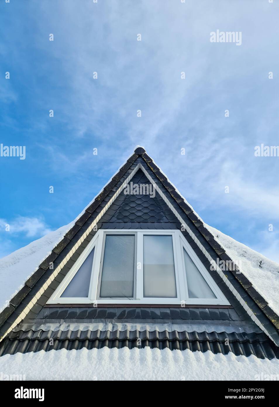 Open roof window in velux style with black roof tiles covered in snow ...