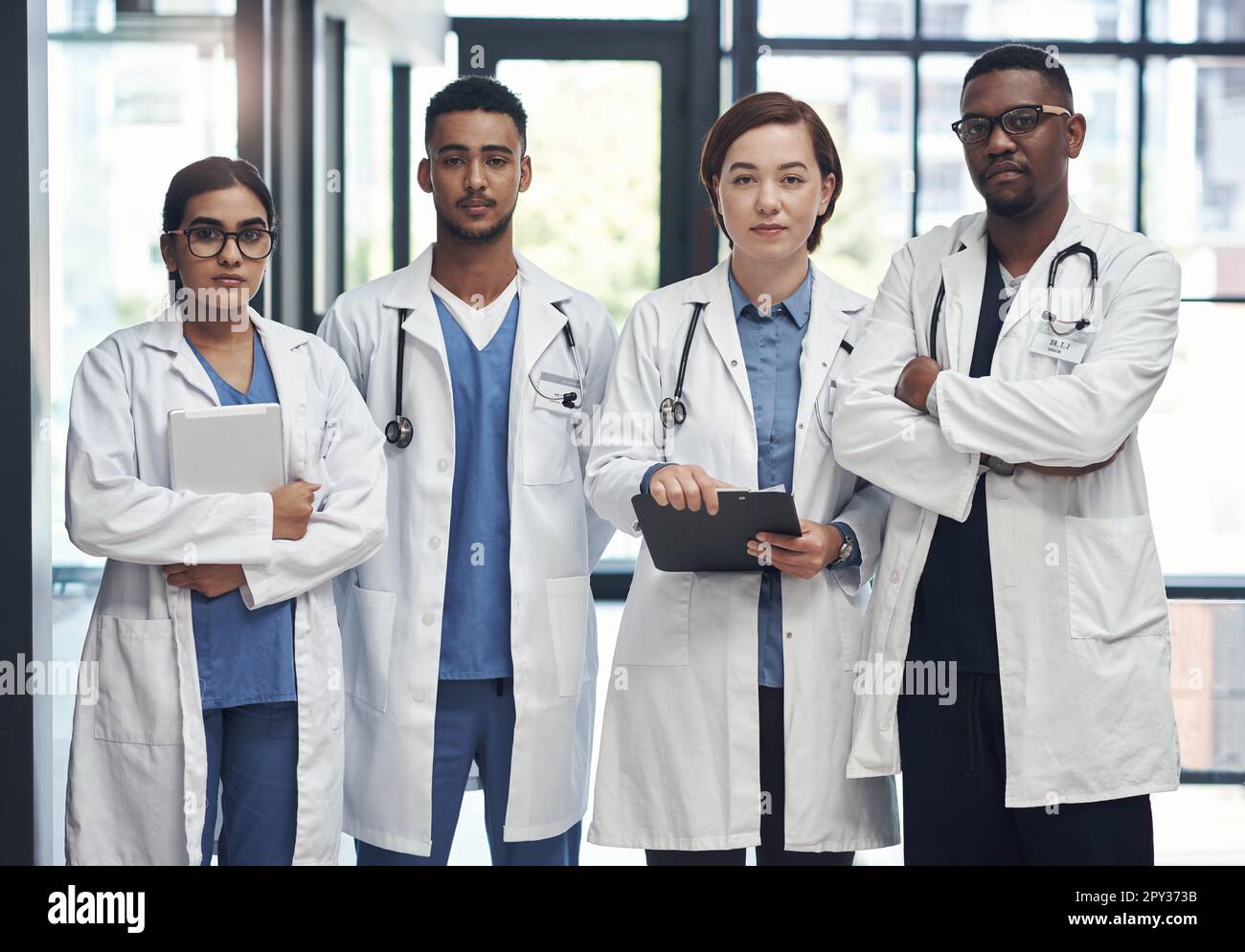 Portrait of african male doctor standing in a row with medical team hi ...