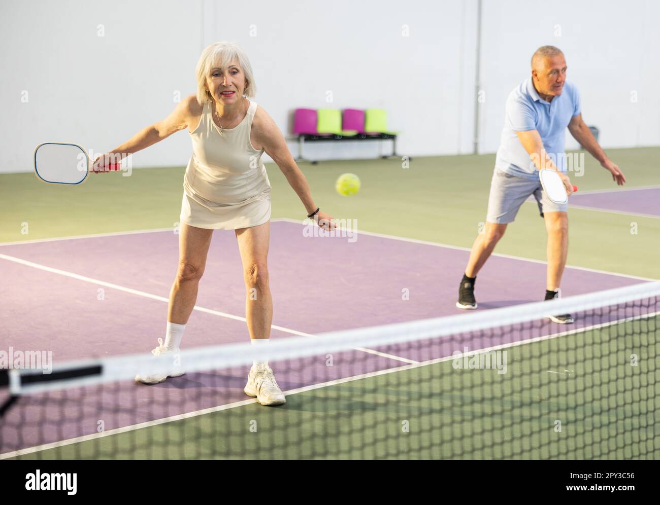 Two pickleball players prepare to return a ball on pickleball court ...
