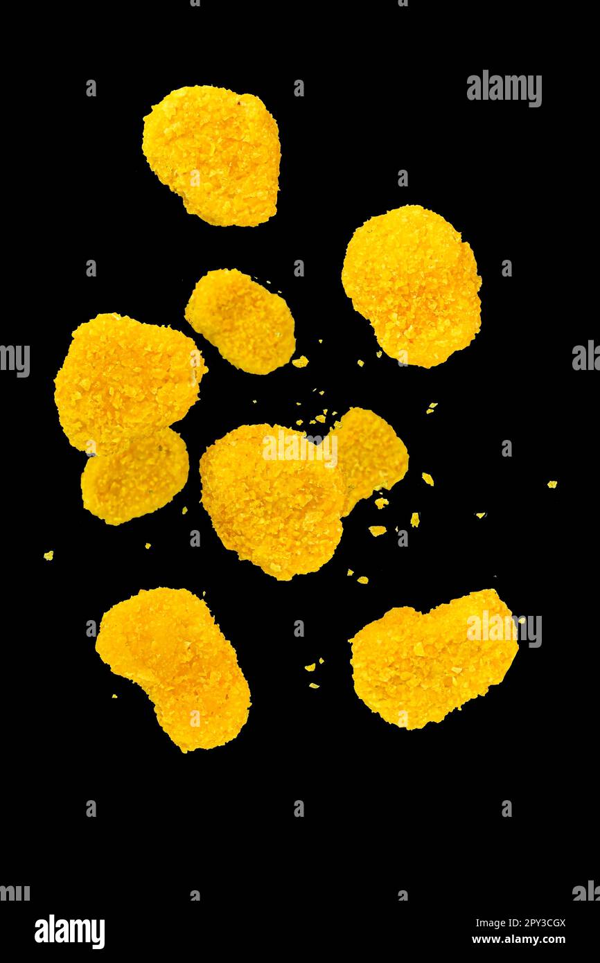 Fresh chicken nuggets falling on black background. Freeze motion of ...
