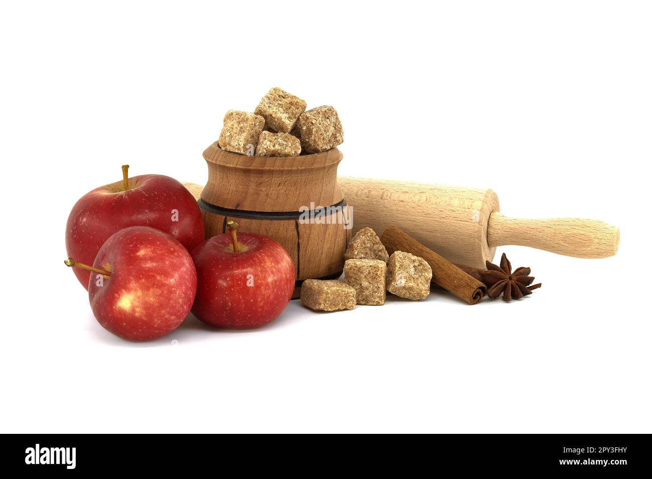 Red apples, sugar, cinnamon sticks and anise stars near rolling pin in ...