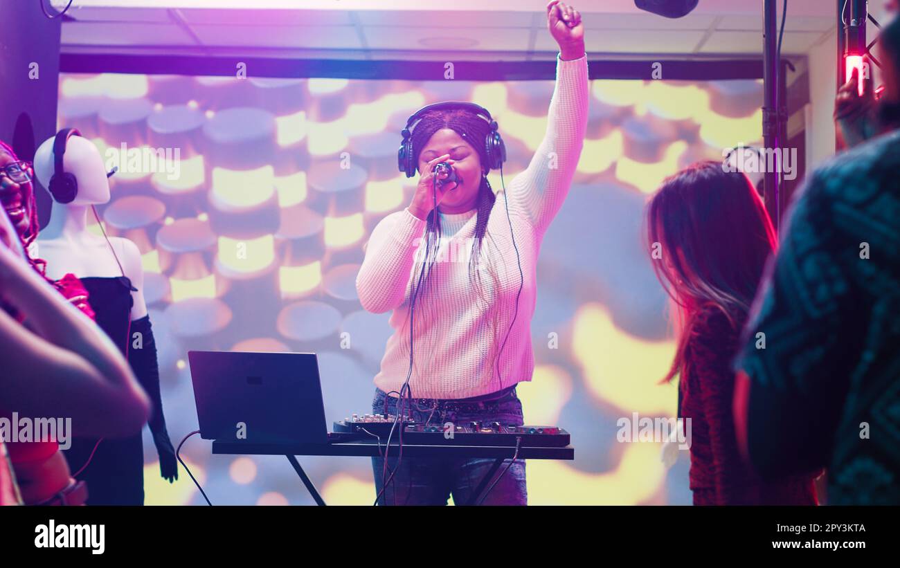 Cheerful girl using DJ station on stage creating electronic live ...