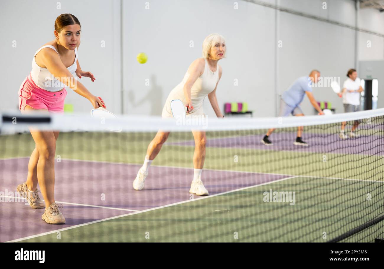 Young girl playing doubles pickleball match with aged female partner ...