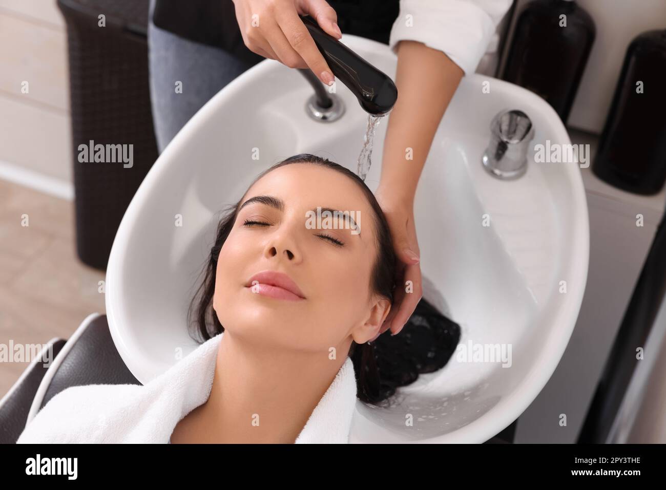Professional hairdresser washing woman's hair in beauty salon, closeup ...