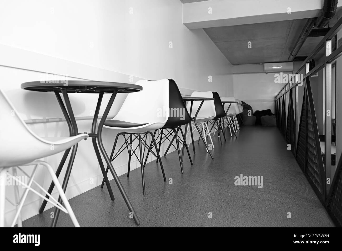 Hostel dining room interior with tables and chairs along white wall ...