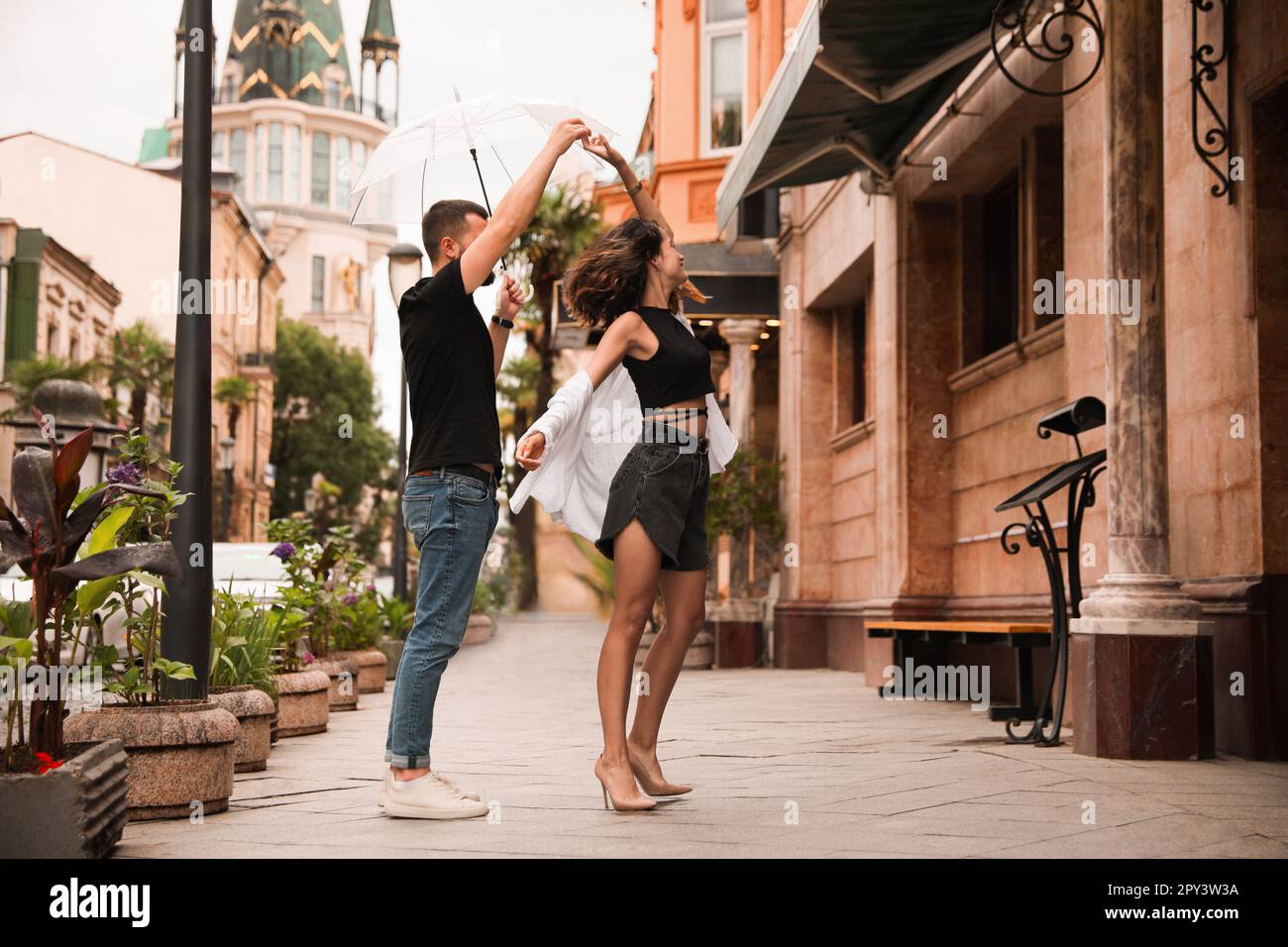 Young couple with umbrella dancing under rain on city street Stock ...