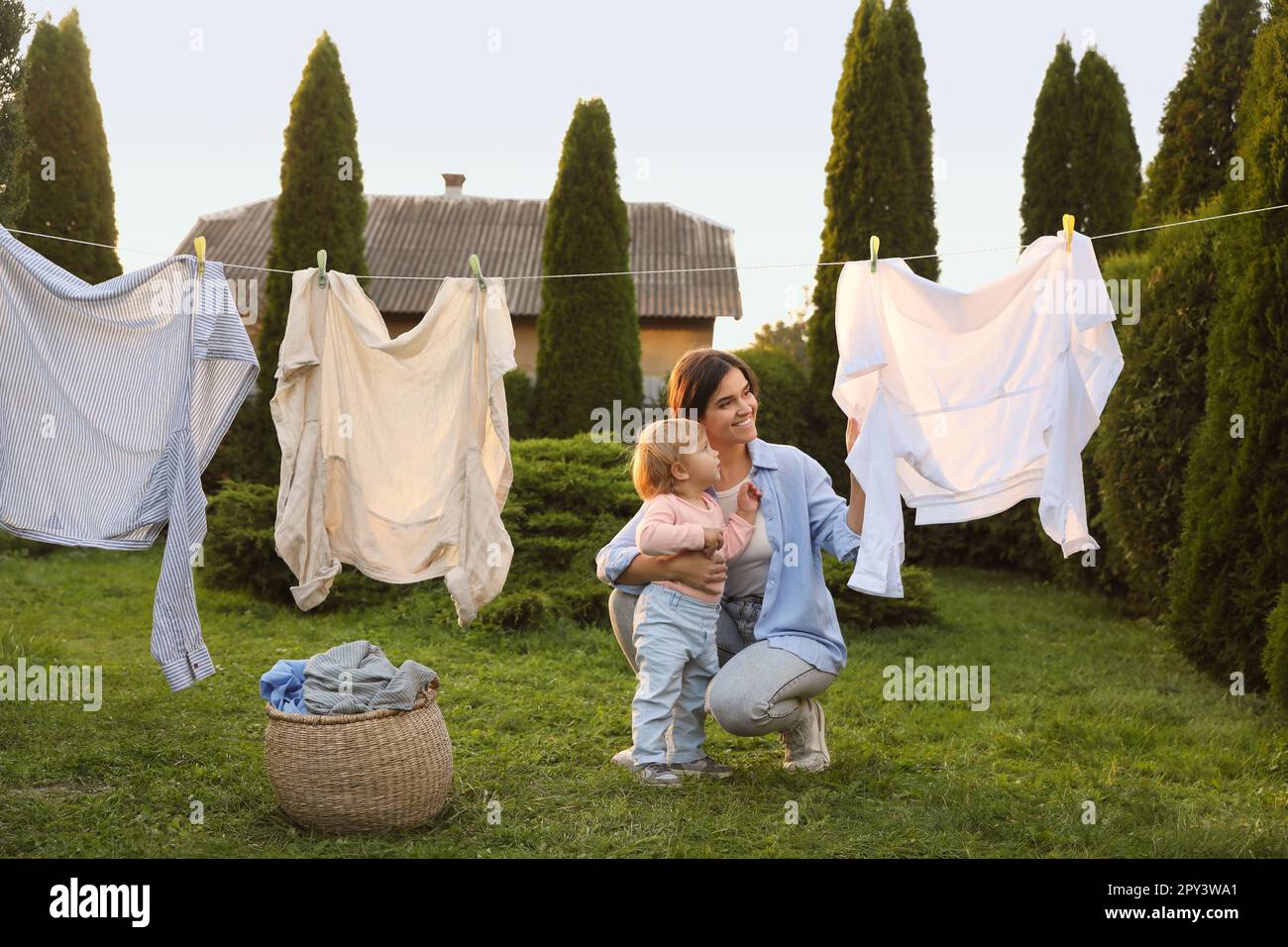 Mother and daughter near washing line with drying clothes in backyard ...