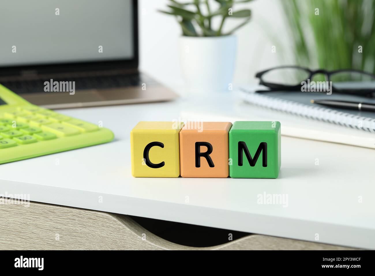 Abbreviation CRM of cubes with laptop on white office table. Customer ...