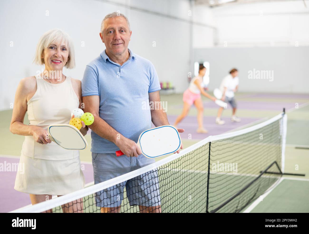 Elderly couple with rackets and balls posing on pickleball court Stock ...
