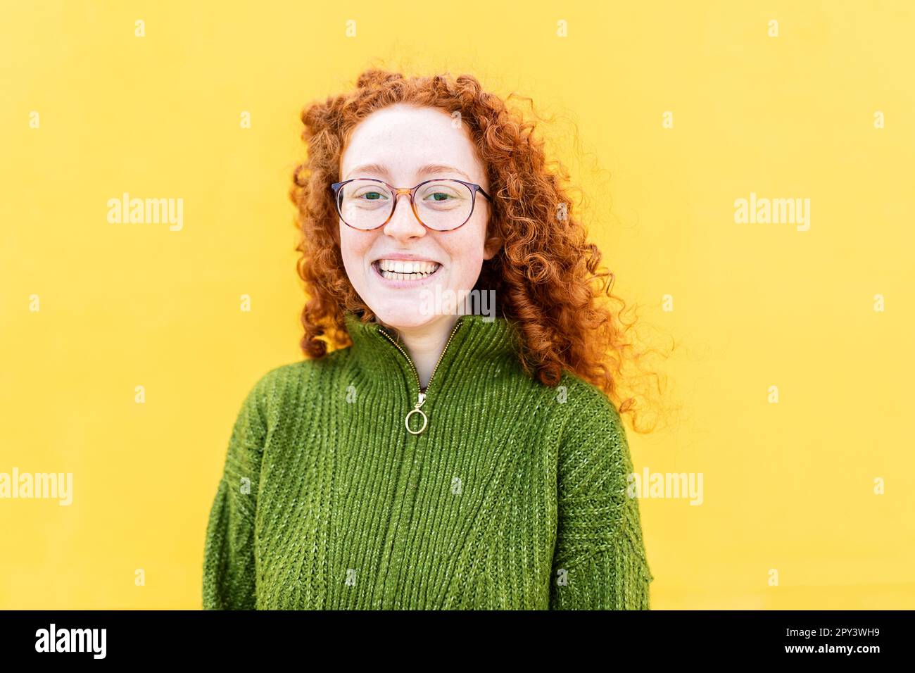 Young ginger woman smiling over yellow background Stock Photo - Alamy